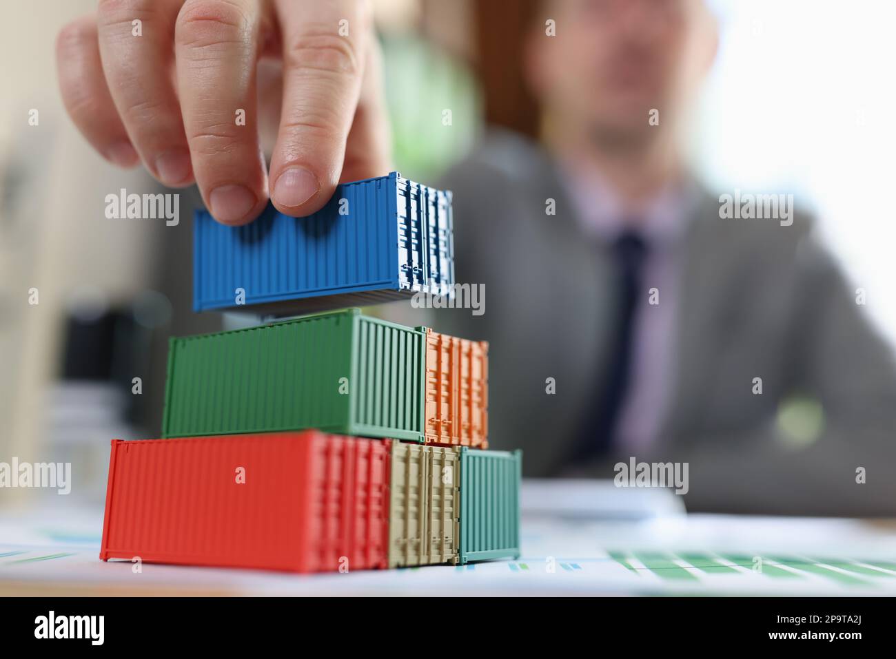 Business man arranging several cargo containers on his table with ...