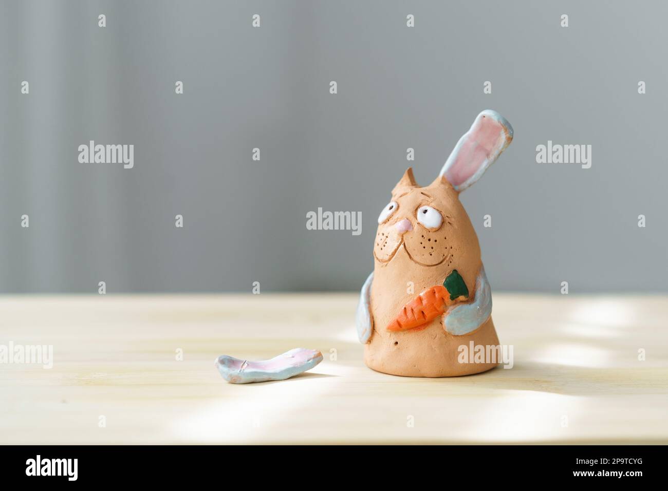 Sad Clay Rabbit Bunny with Broken Ear Holds Carrot And Looking Away ...
