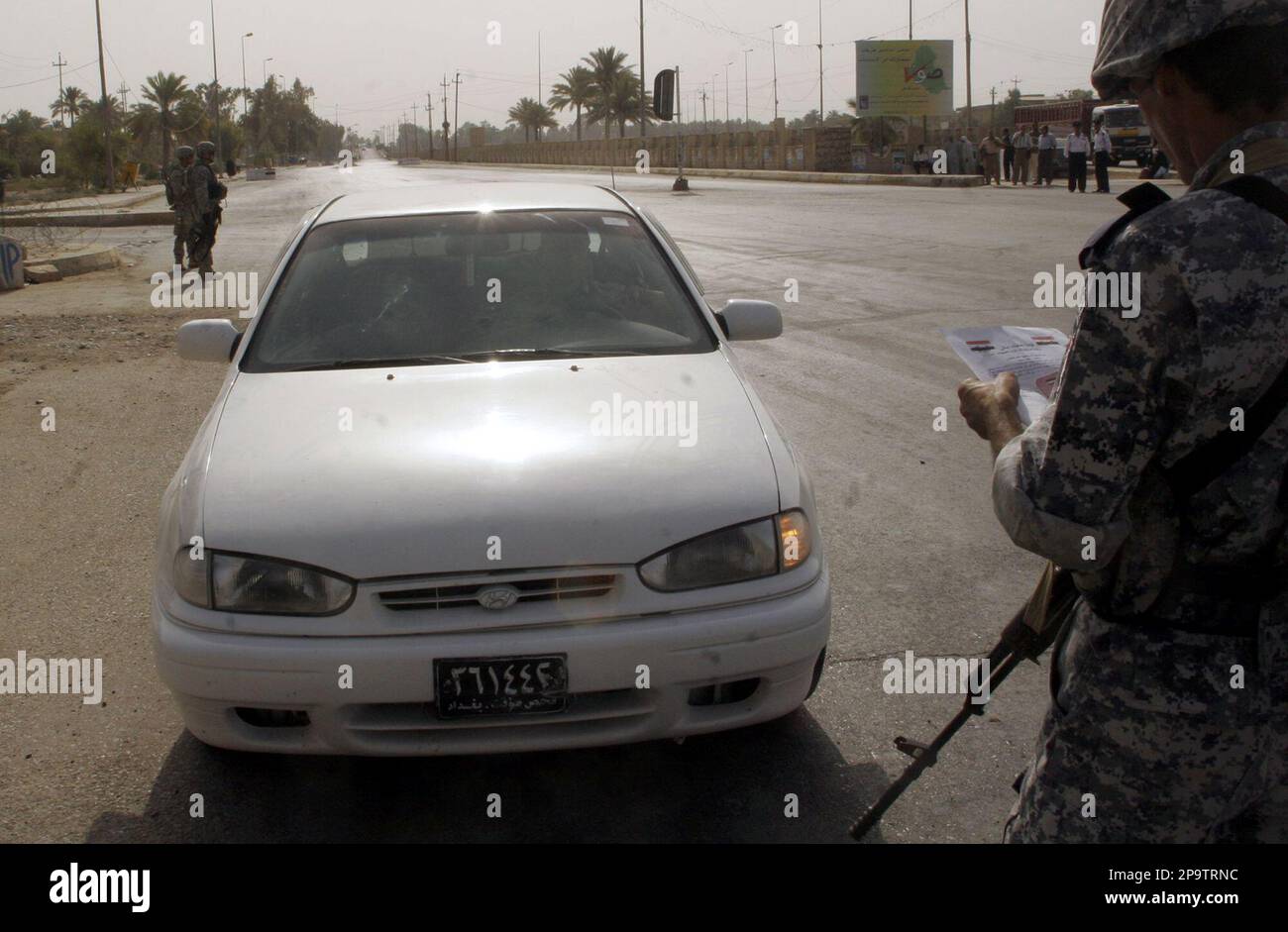 An Iraqi police officer stops a car at a newly established vehicle ...
