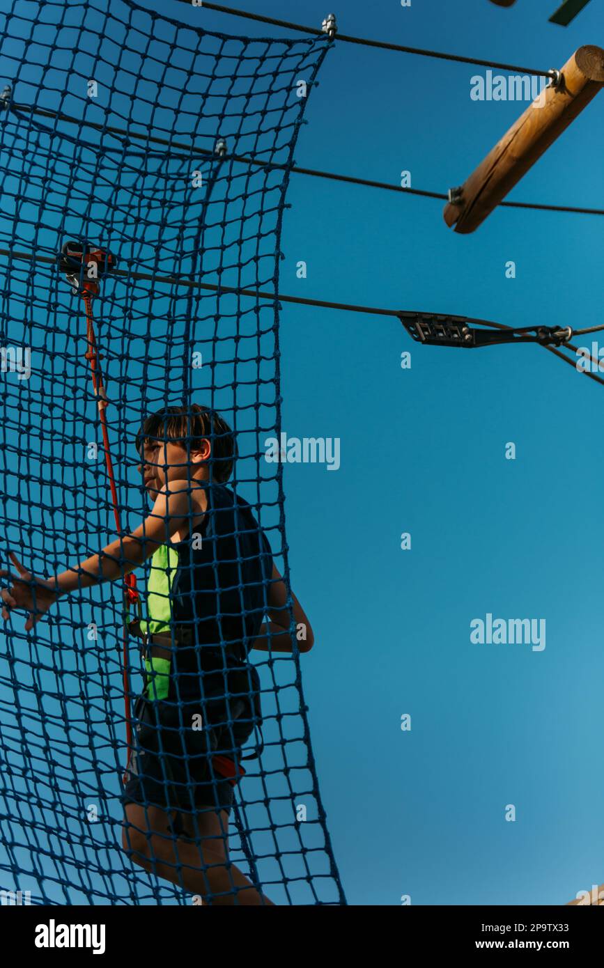 Young schoolboy struggling in the tough net bridge in the adventure ...