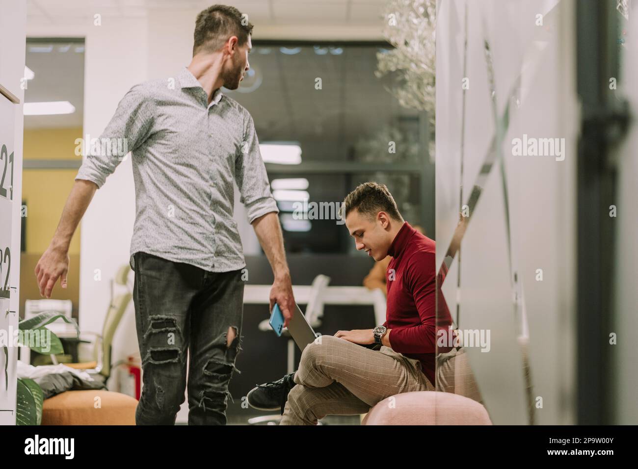 Male person walking in the office while looking back at his colleague ...