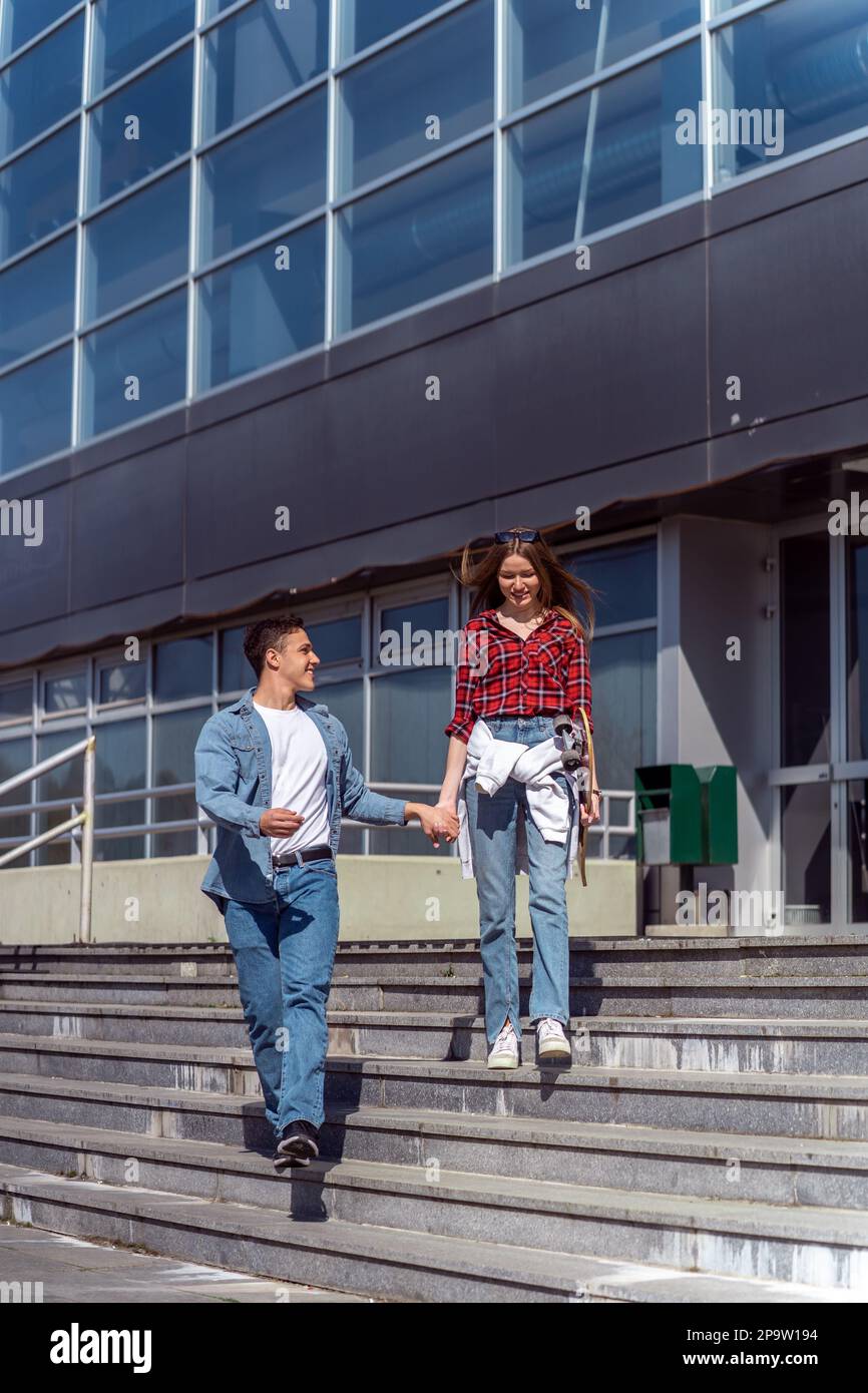 Pretty couple walking on the stairs in front of the building while ...