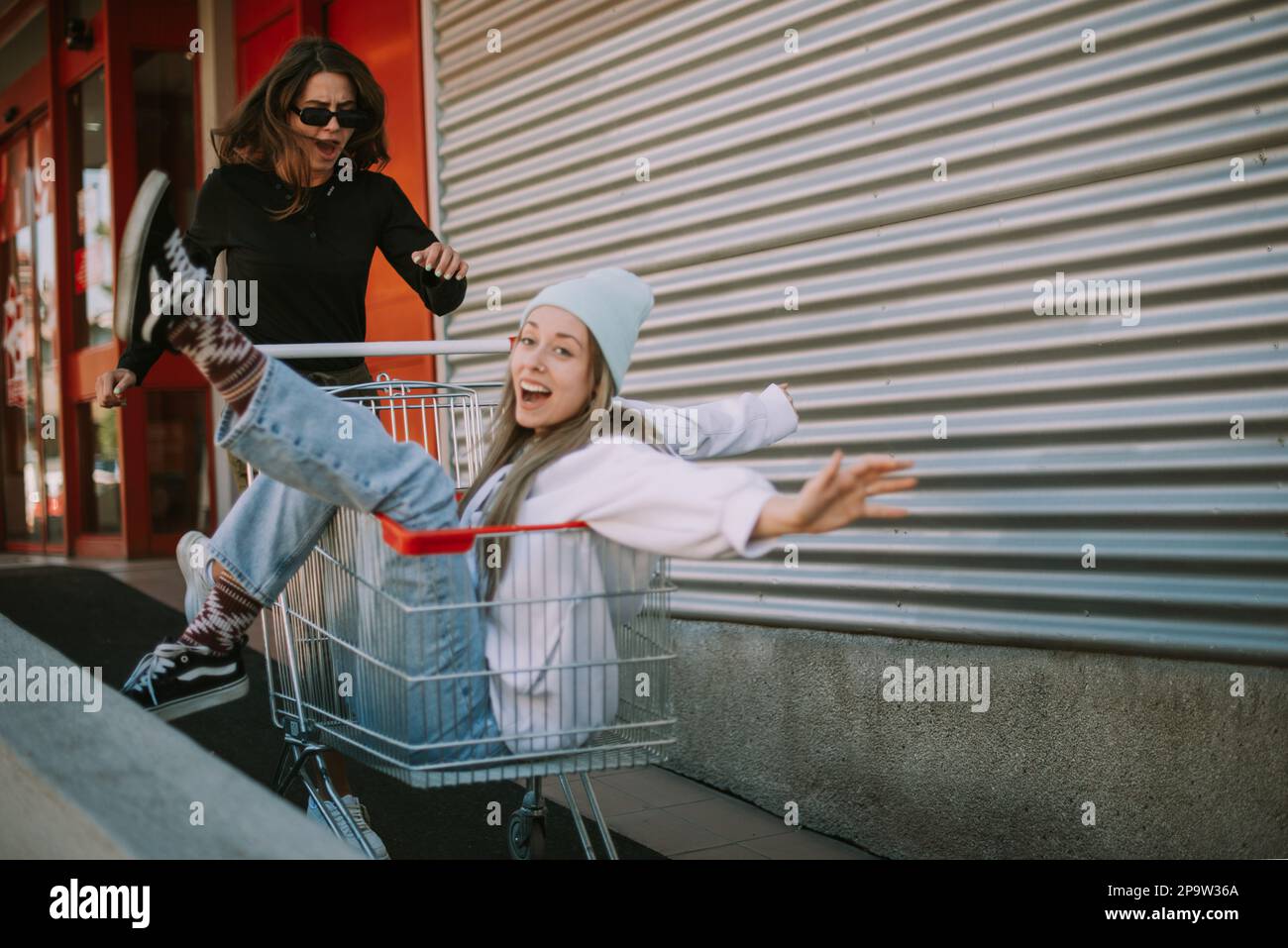 Brunette girl running after the market cart with her best friend in it ...