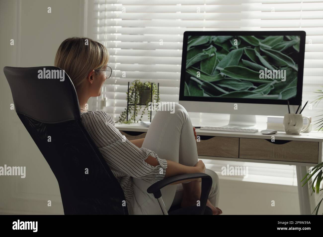 Woman resting on chair near workplace in room. Interior design Stock ...