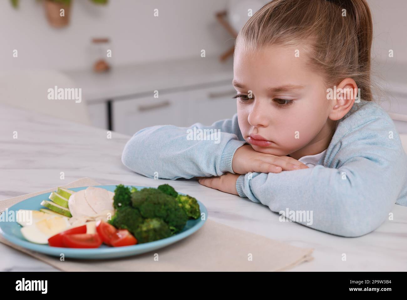 Cute little girl refusing to eat dinner in kitchen Stock Photo - Alamy