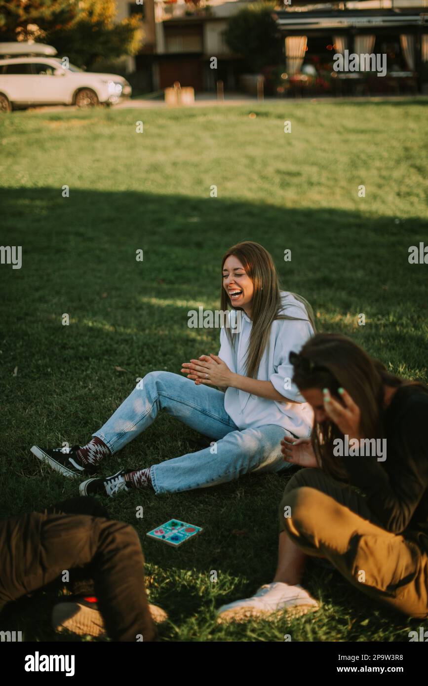 Beautiful blonde girl laughing with her friends while playing ludo ...
