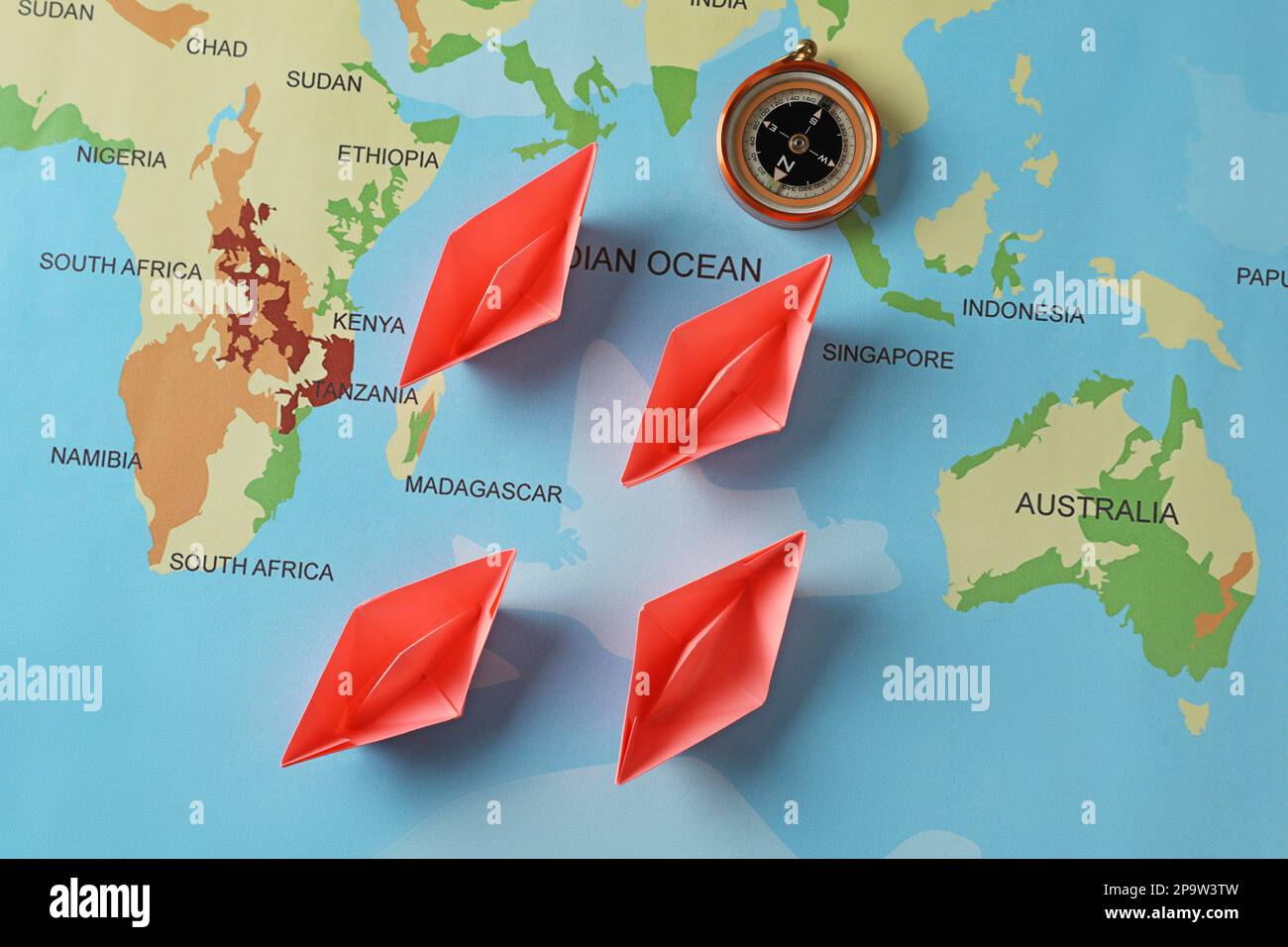 Bright paper boats and compass on world map, flat lay Stock Photo - Alamy