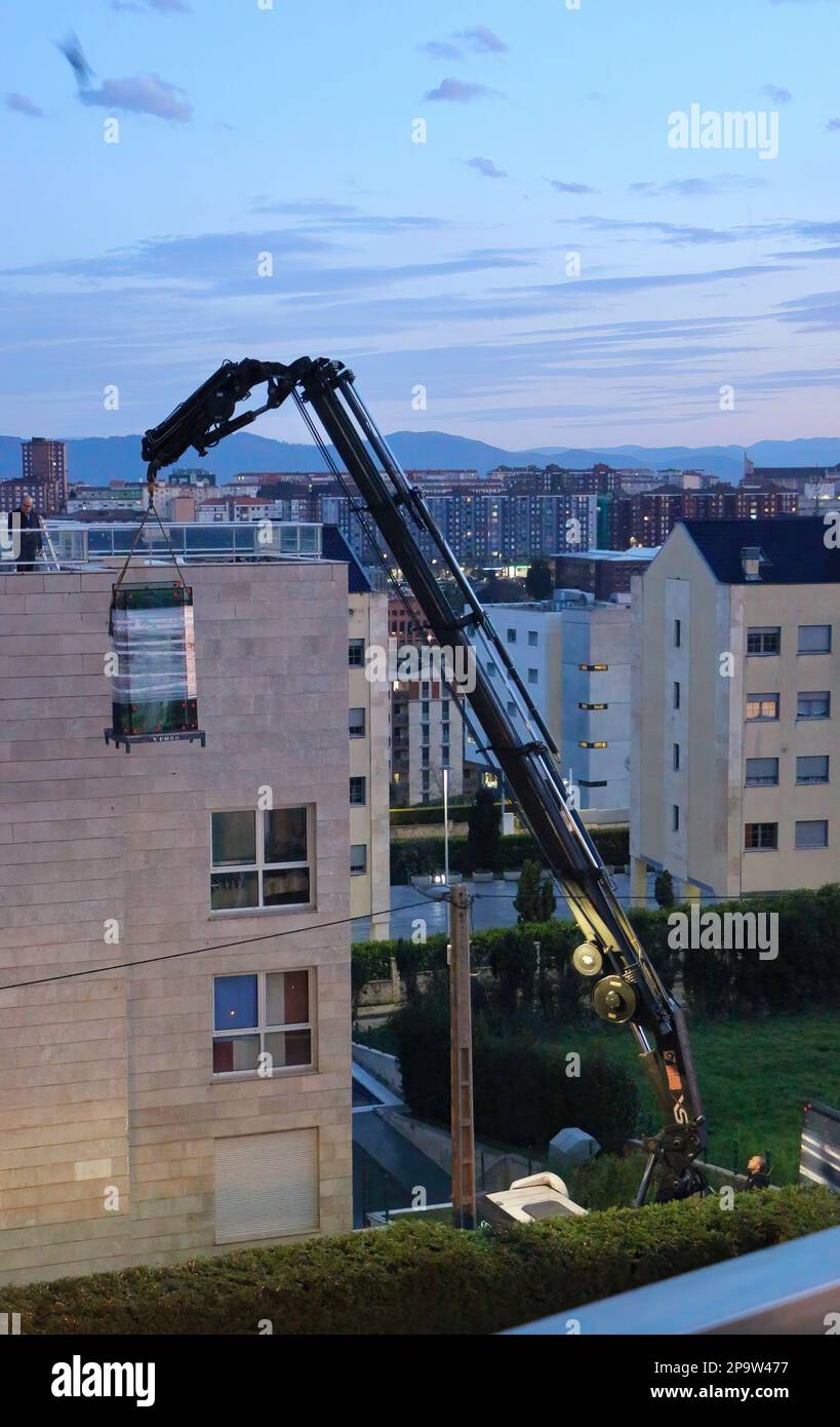 Glass panels being delivered to the flat roof of a block of flats by a ...