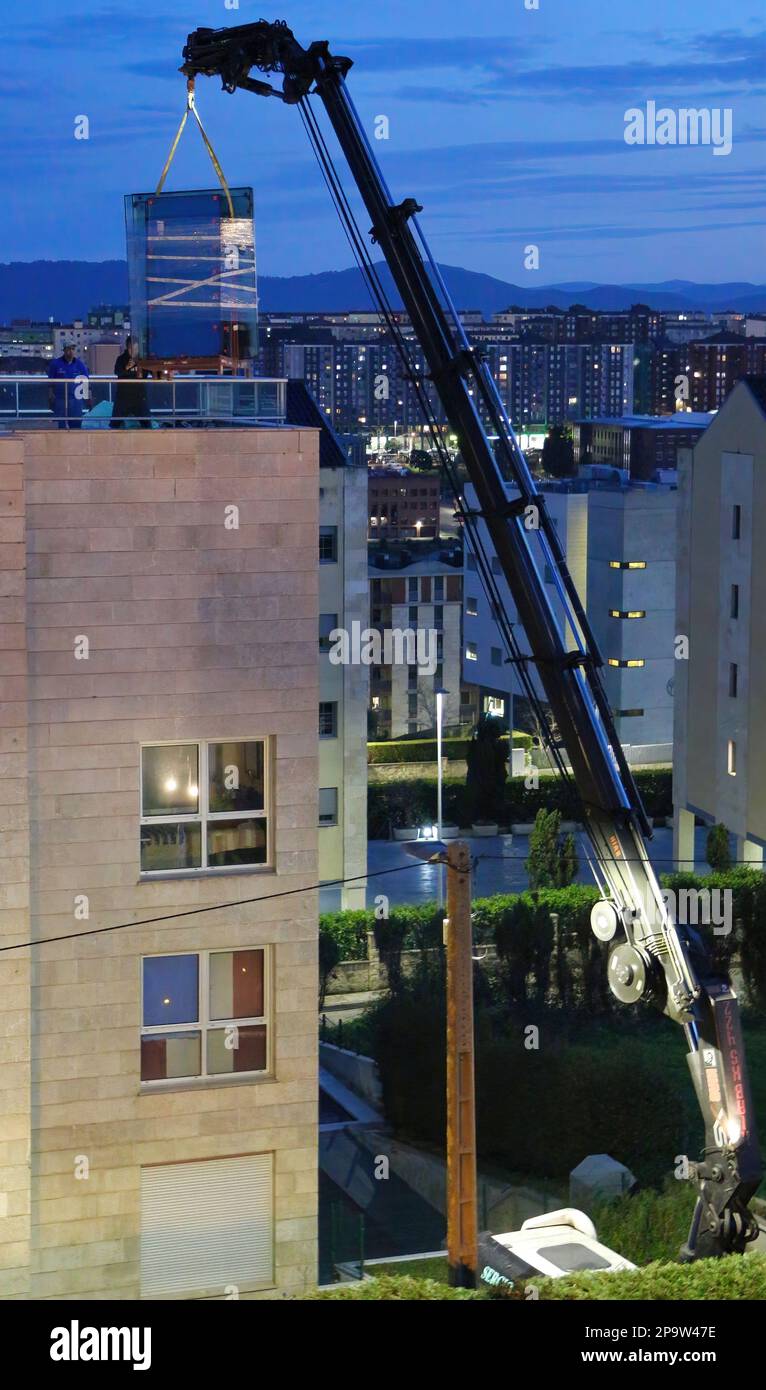 Glass panels being delivered to the flat roof of a block of flats by a ...