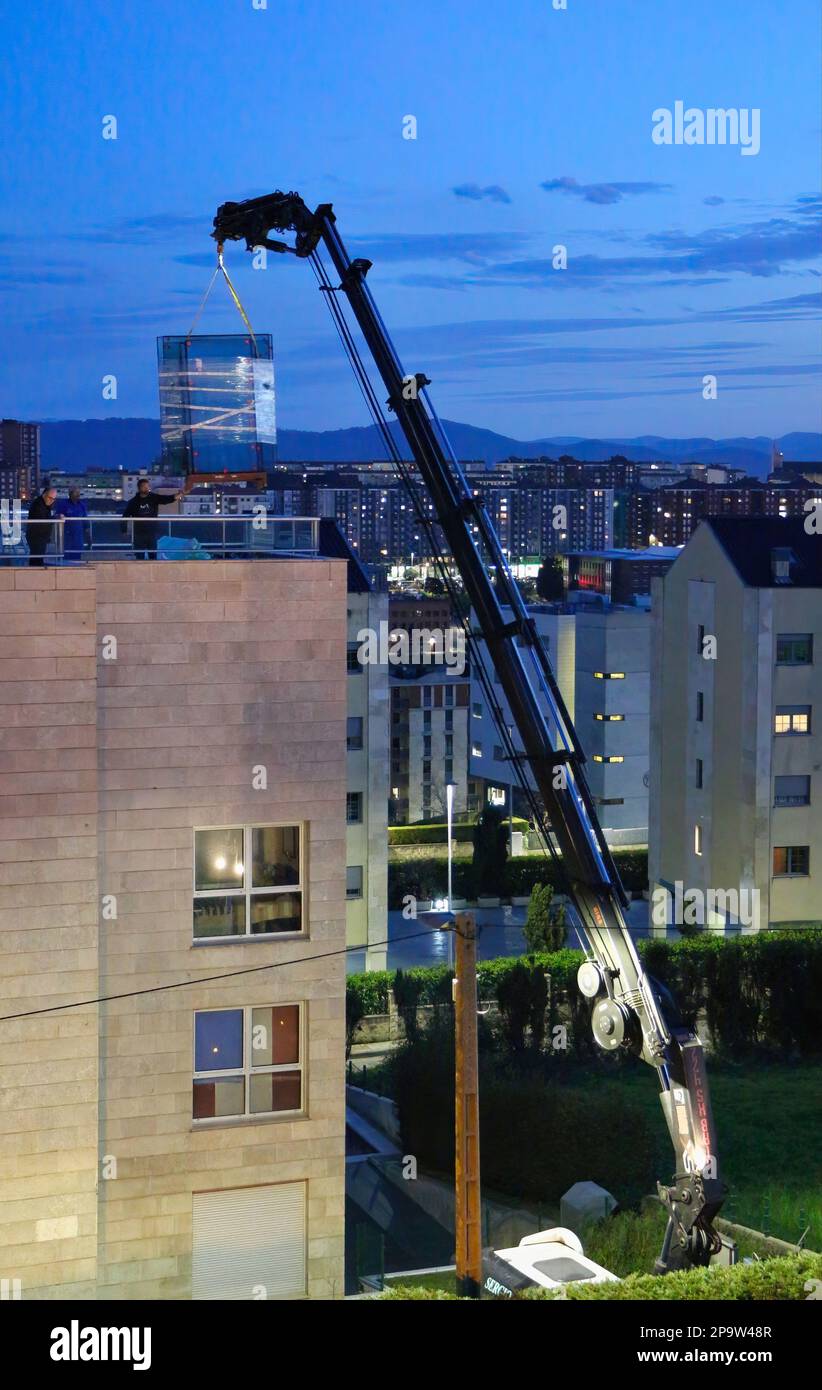 Glass panels being delivered to the flat roof of a block of flats by a ...