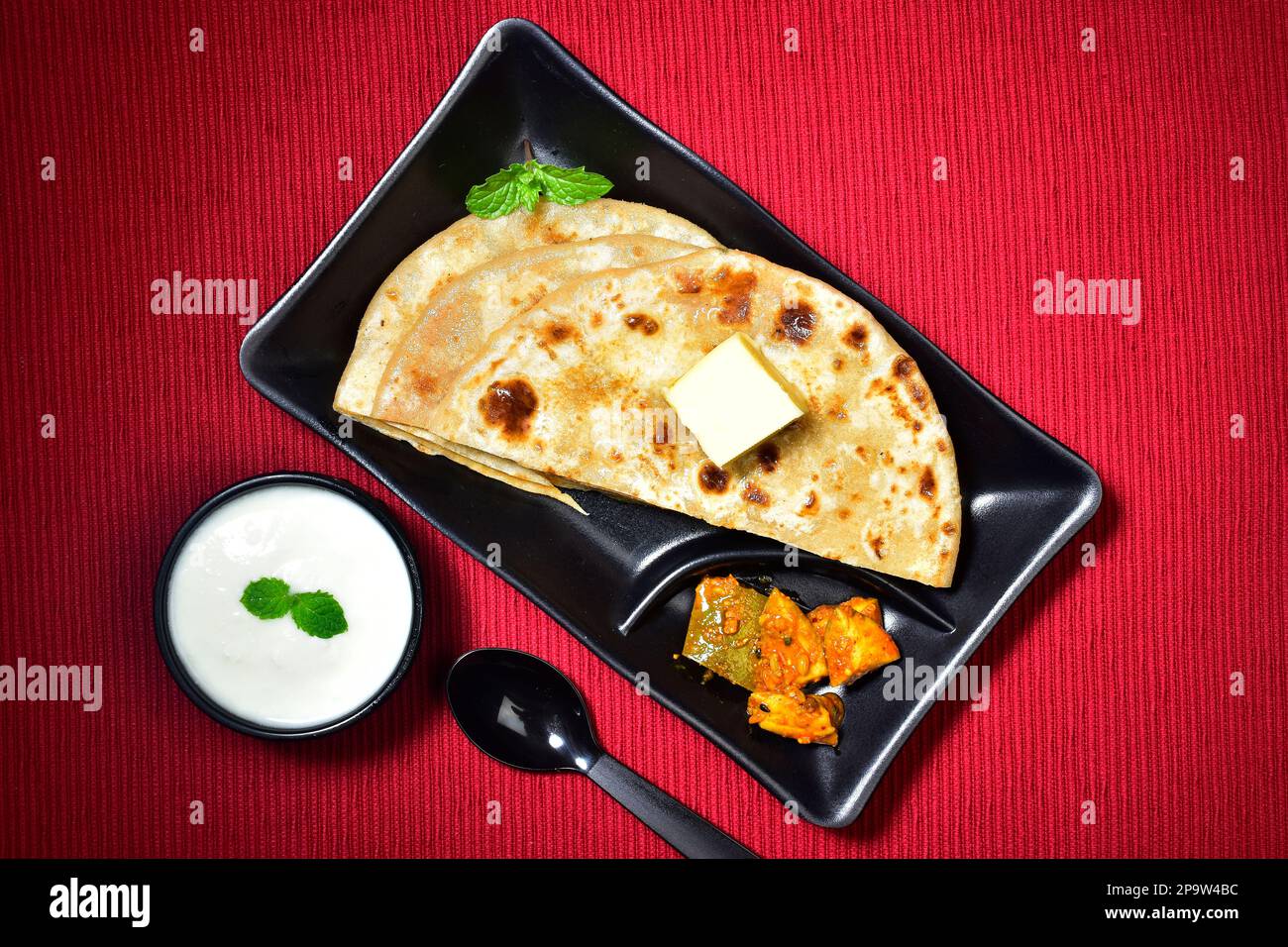 Top view of butter paratha served with pickle and dahi in plate ...