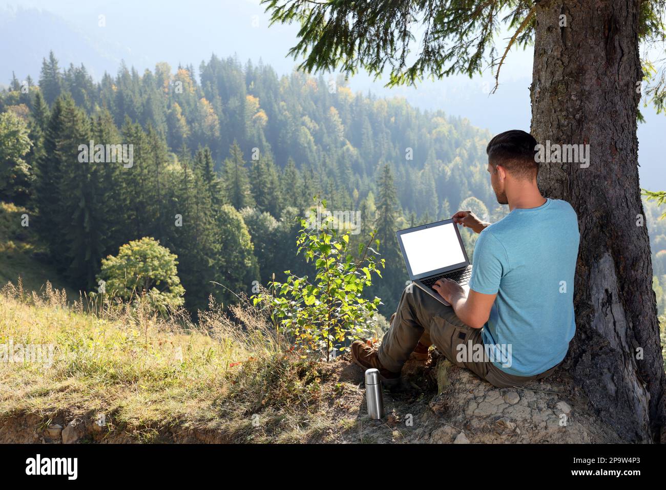 Man working on laptop outdoors surrounded by beautiful nature, back ...
