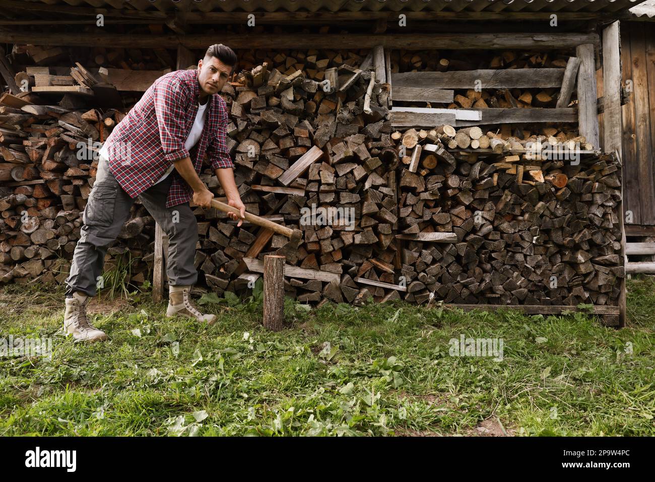 Man chopping wood near log pile outdoors Stock Photo - Alamy