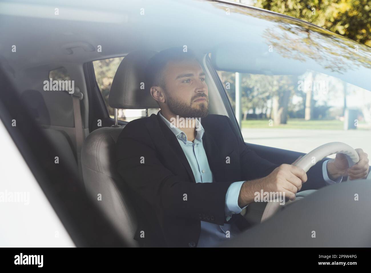 Handsome young driver sitting in modern car, view through windshield ...