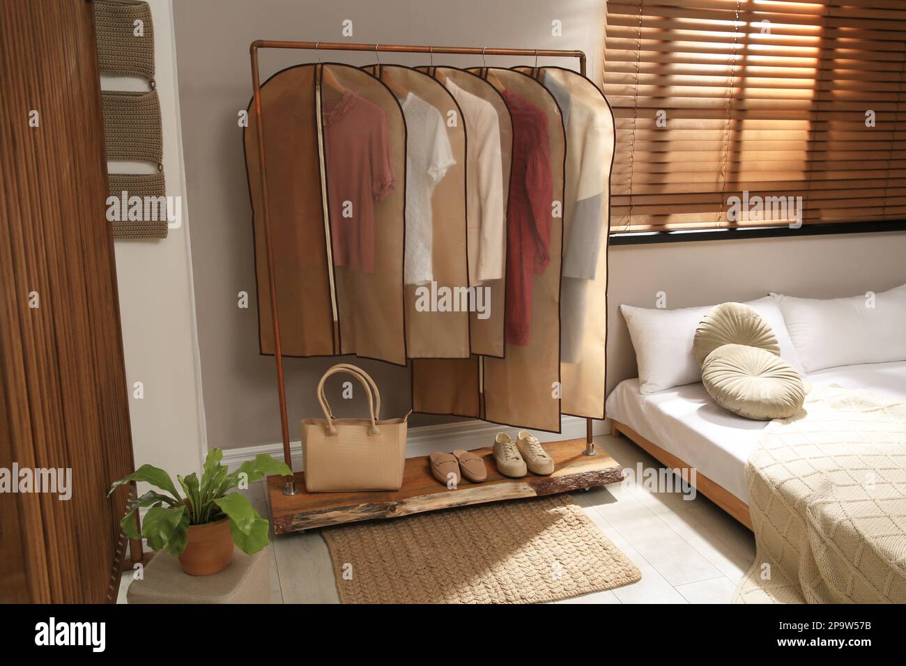 Garment bags with clothes hanging on rack in bedroom Stock Photo - Alamy