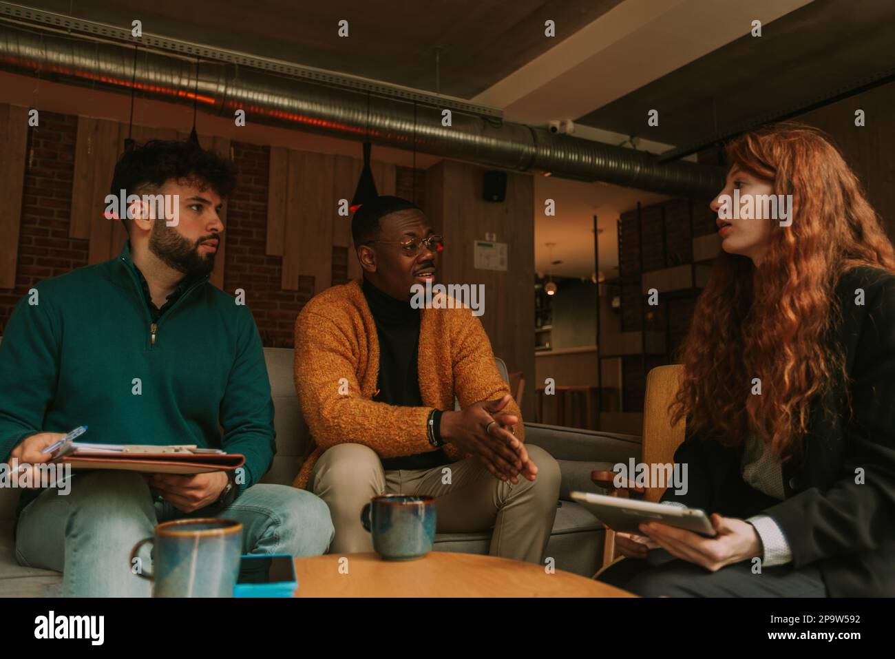 Three multiracial colleagues working remotely at the coffee bar on a ...