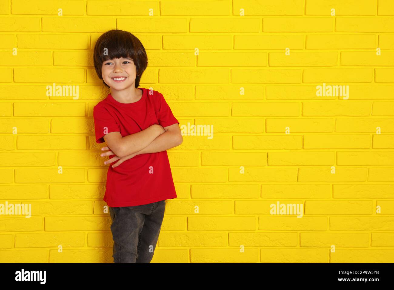 Cute little boy near yellow brick wall, space for text Stock Photo - Alamy