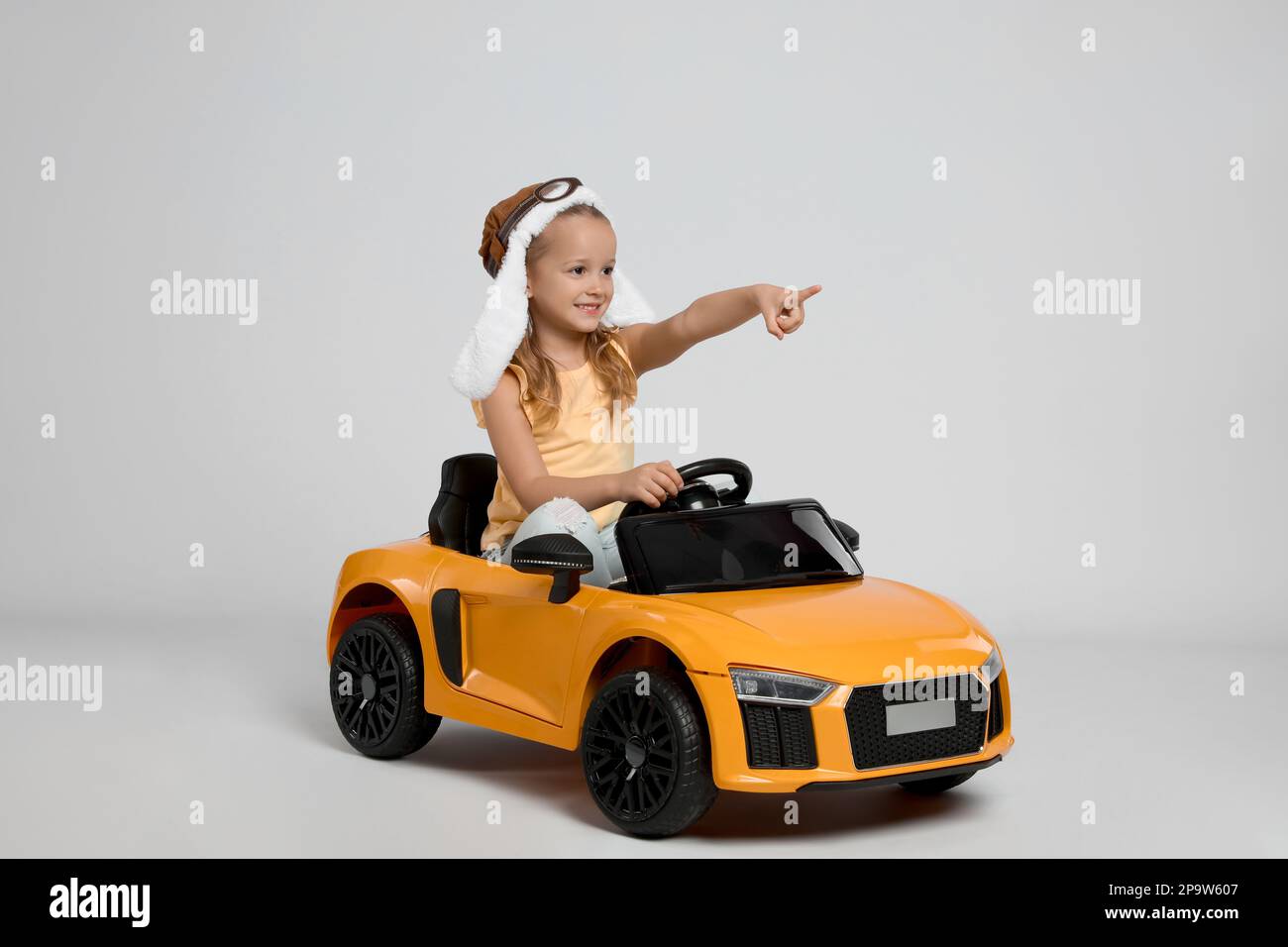 Cute little girl in pilot hat driving children's electric toy car on ...