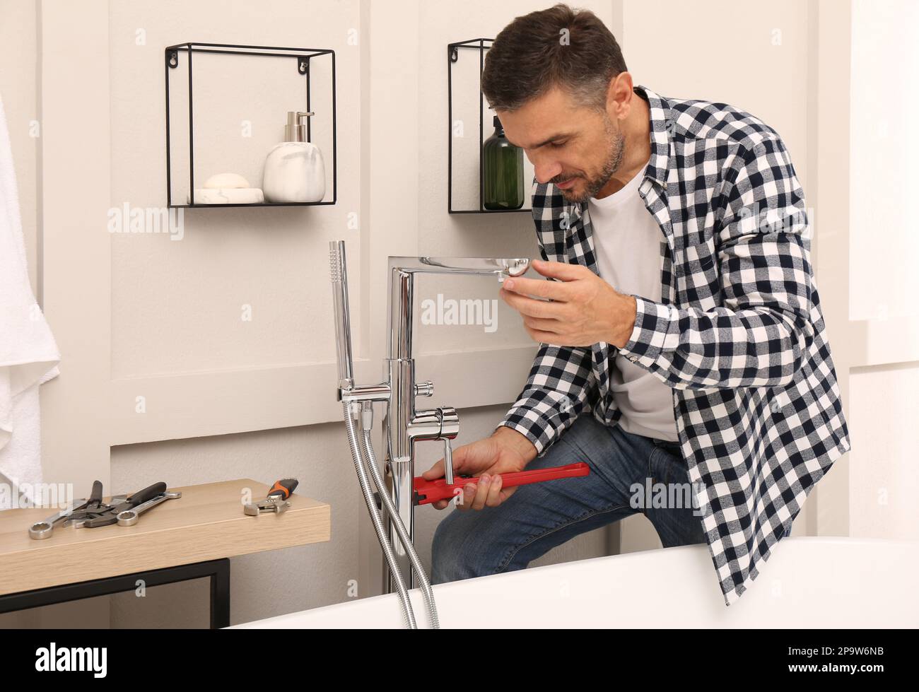 Man installing water tap with shower head in bathroom Stock Photo - Alamy