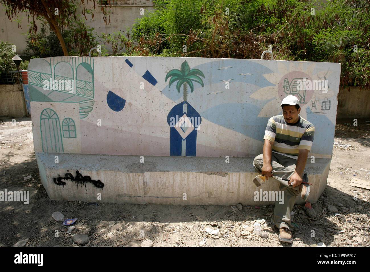 Ali Saleem Badran, a blast wall artist, sits beside a painted blast ...