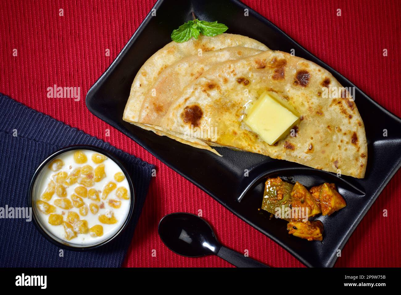 Top view of butter paratha served with boondi raita and mango pickle ...