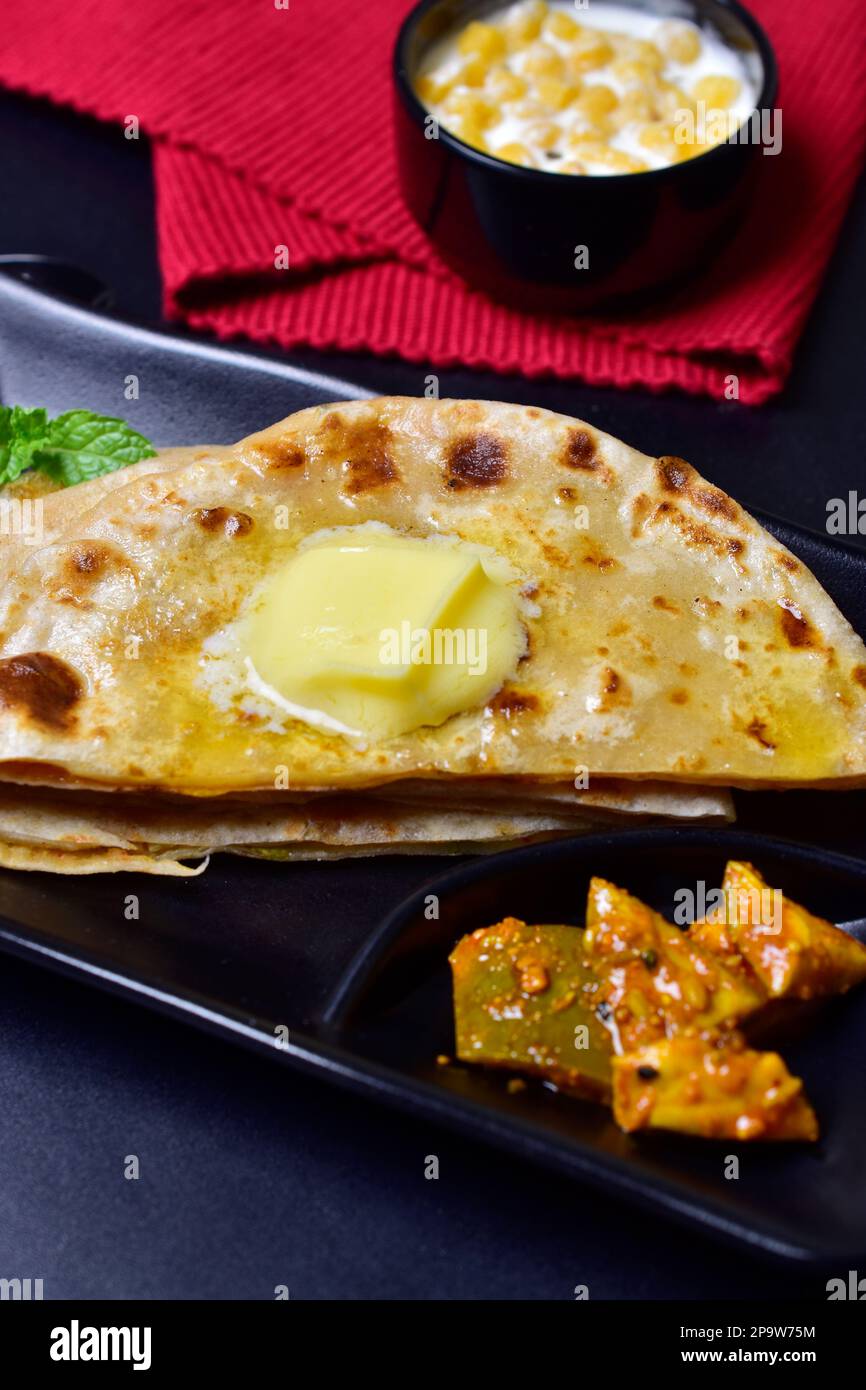 Melted butter on paratha served with pickle and boondi raita Stock ...