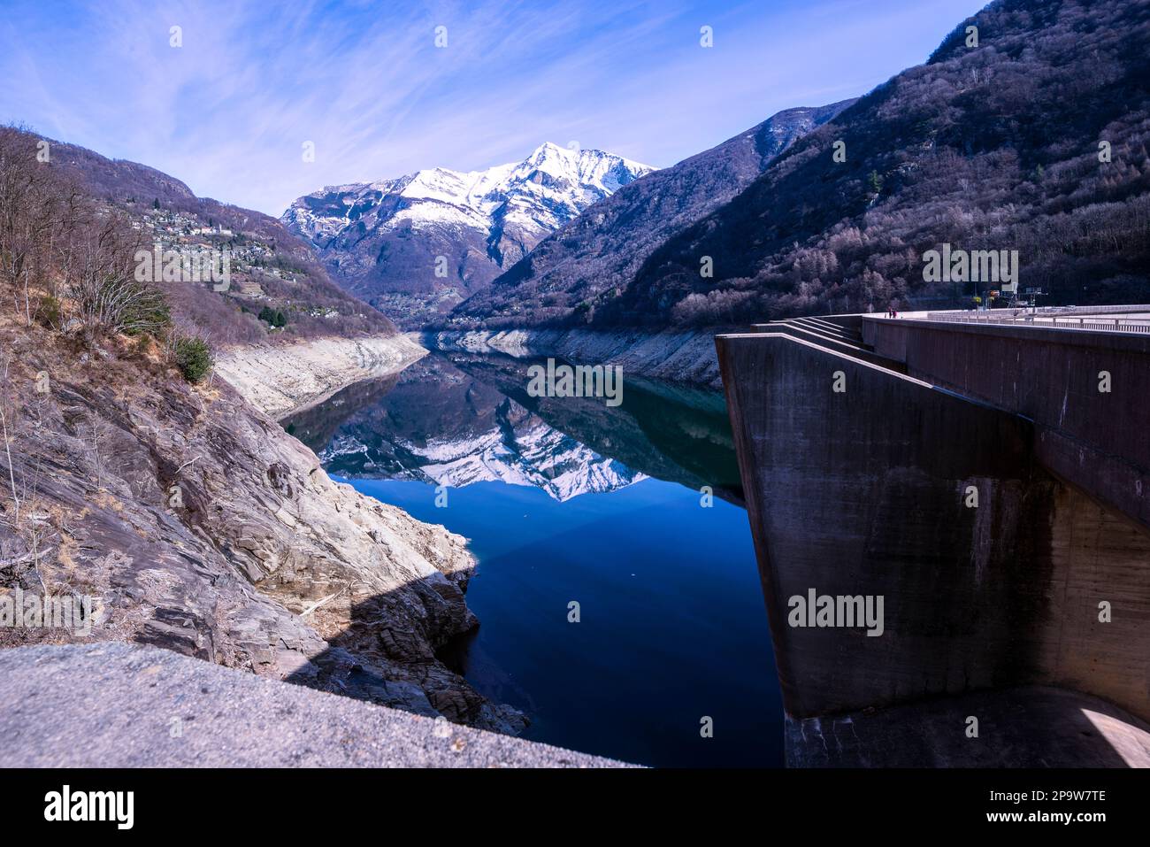 Snow topped mountains mirrored on the surface of the blue reservoir ...