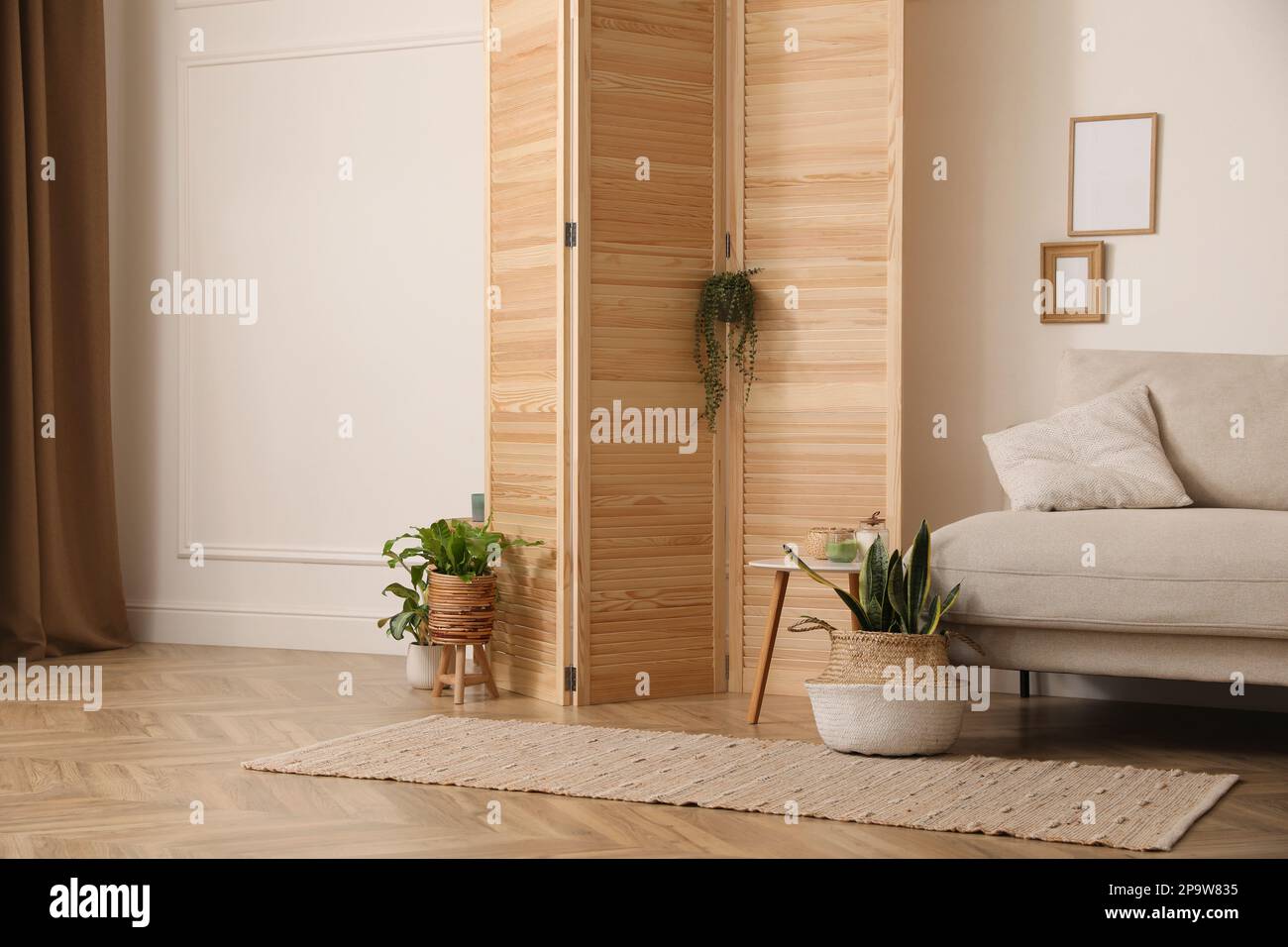 Stylish room with wooden folding screen and comfortable sofa near white ...