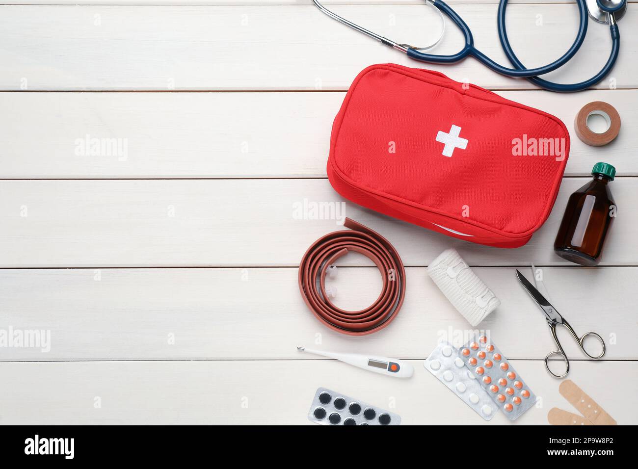 Flat lay composition with first aid kit on white wooden table, space ...