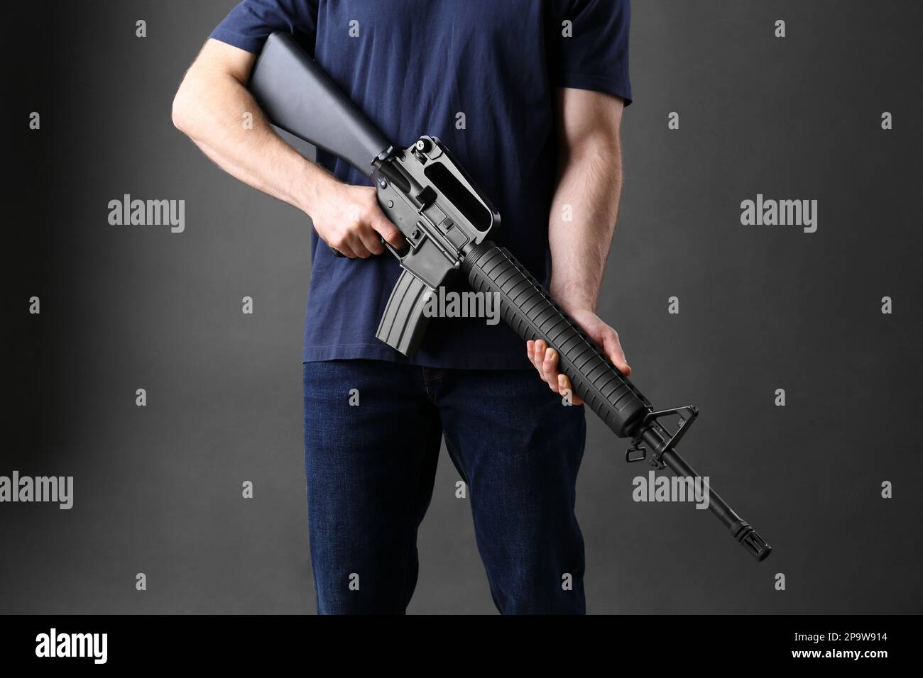 Assault gun. Man holding rifle on dark background, closeup Stock Photo ...