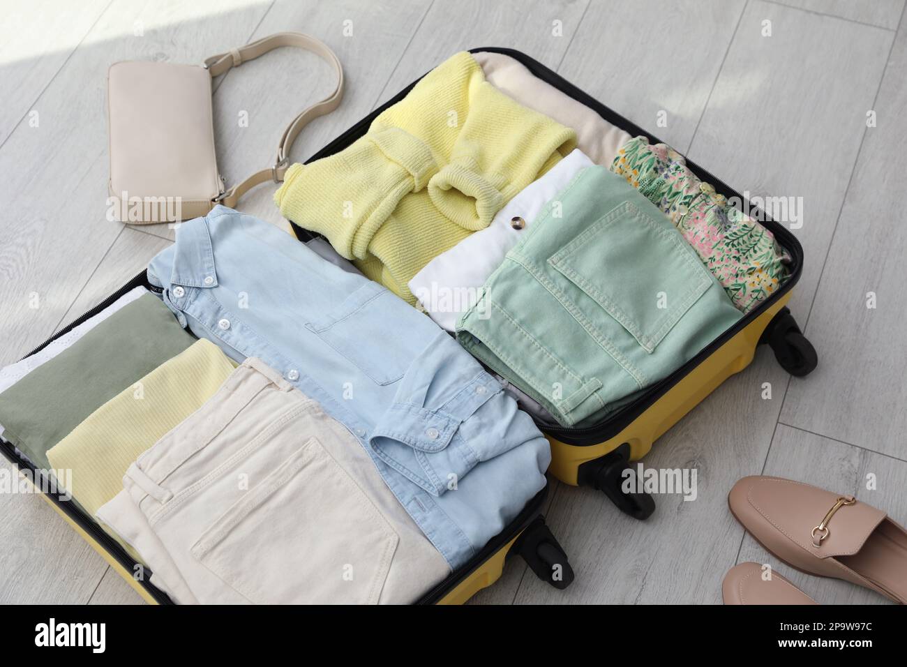 Open suitcase packed for trip, handbag and shoes on floor Stock Photo ...