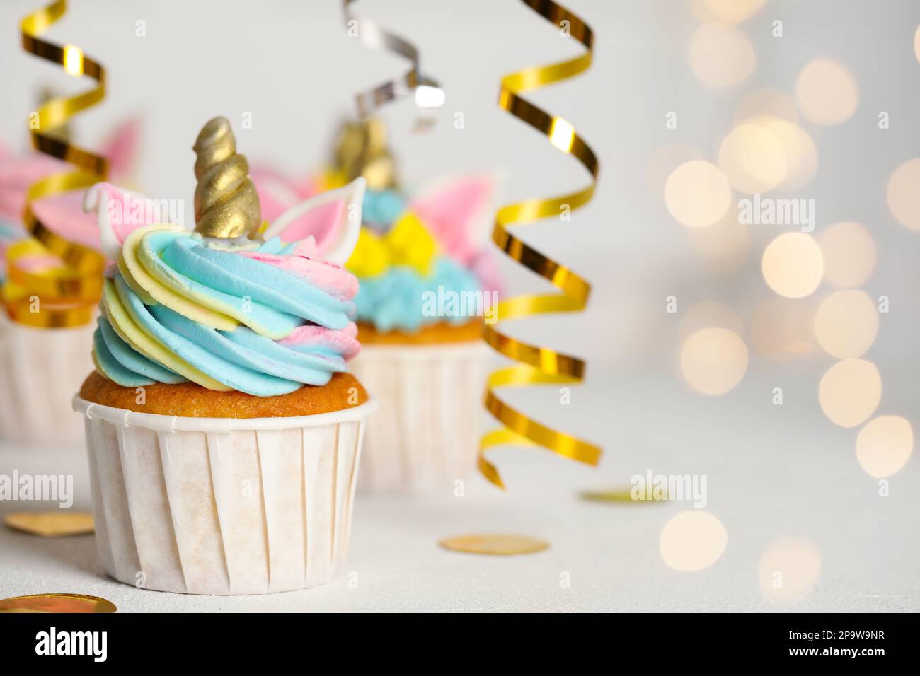 Cute sweet unicorn cupcake on white table, space for text and bokeh ...