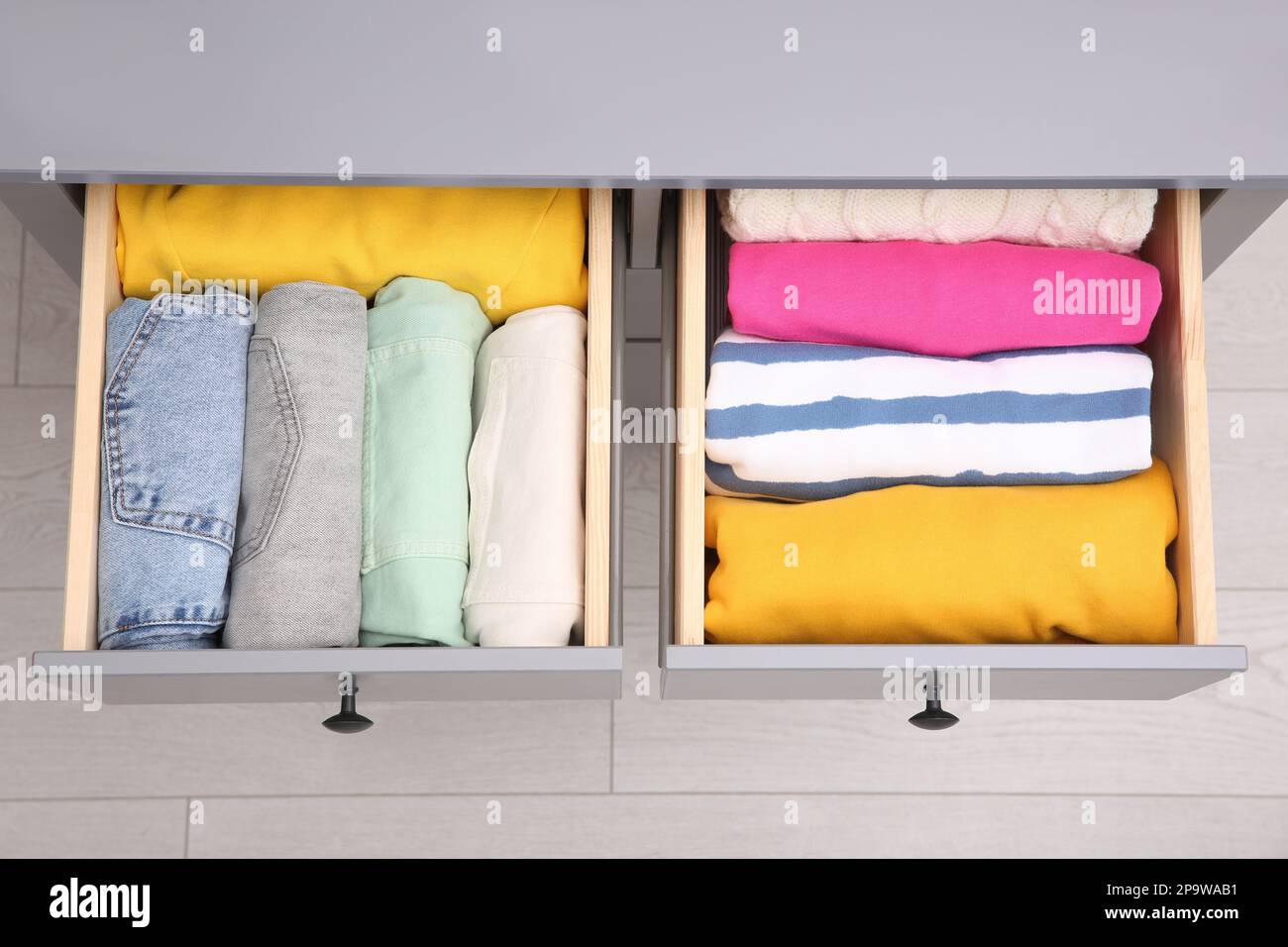 Open drawers with folded clothes indoors, top view. Vertical storage ...