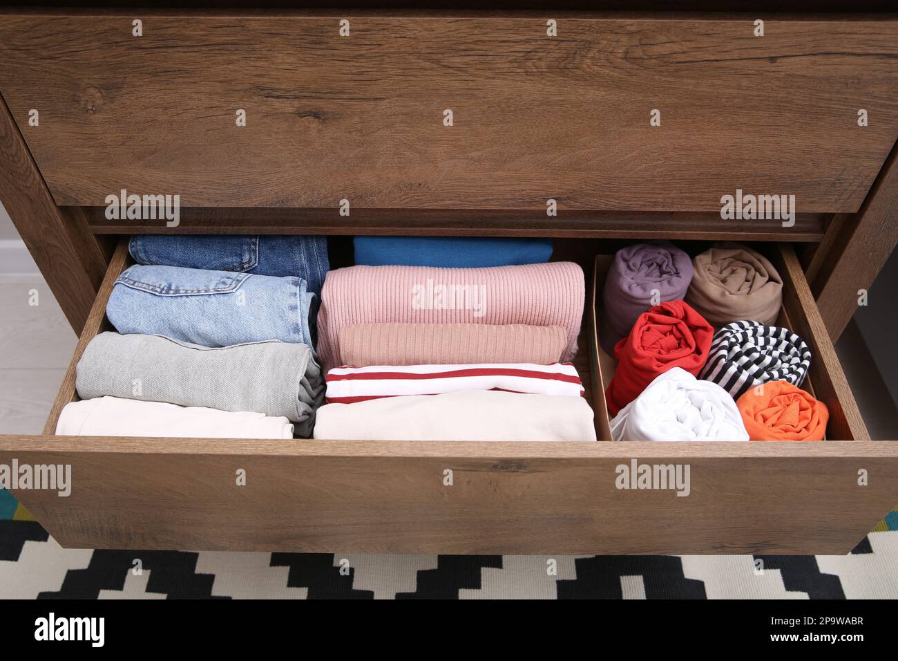 Open drawer with folded clothes indoors. Vertical storage of clothing ...