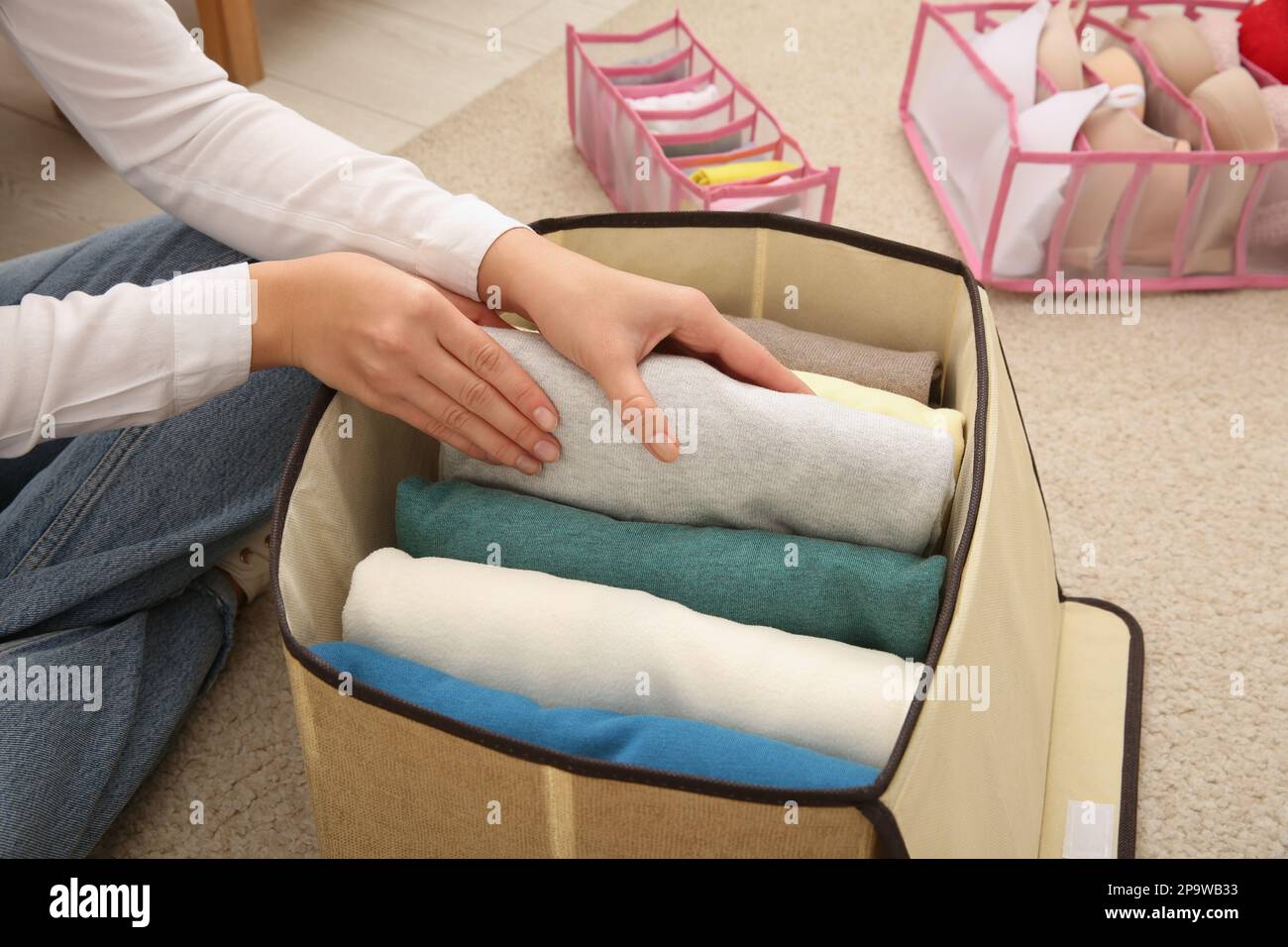 Woman folding clothes on floor, closeup. Japanese storage system Stock ...