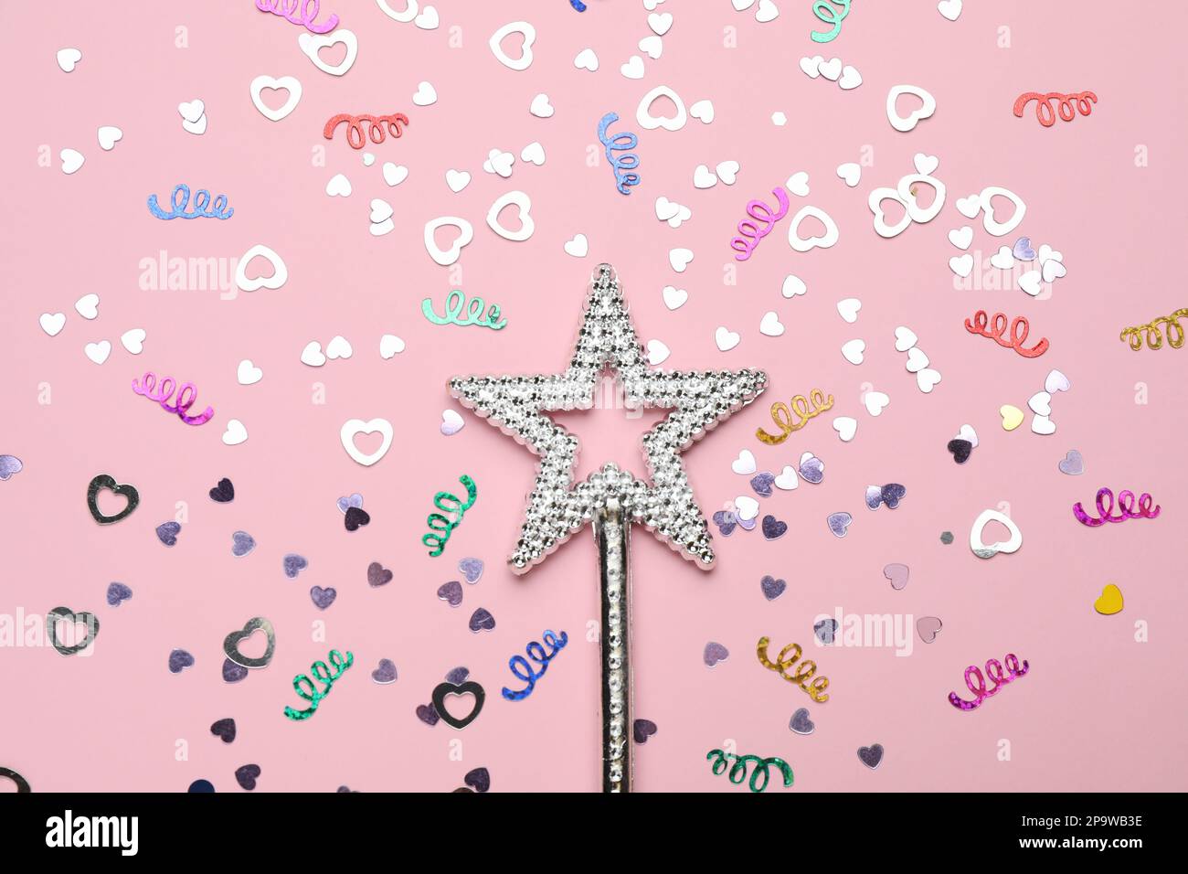Beautiful silver magic wand and confetti on pink background, flat lay ...
