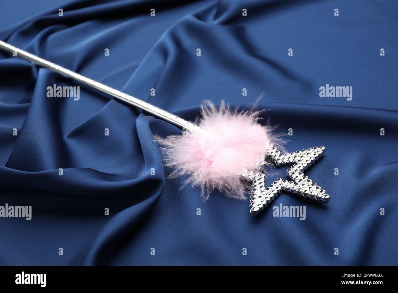 Beautiful silver magic wand with feather on blue fabric Stock Photo - Alamy