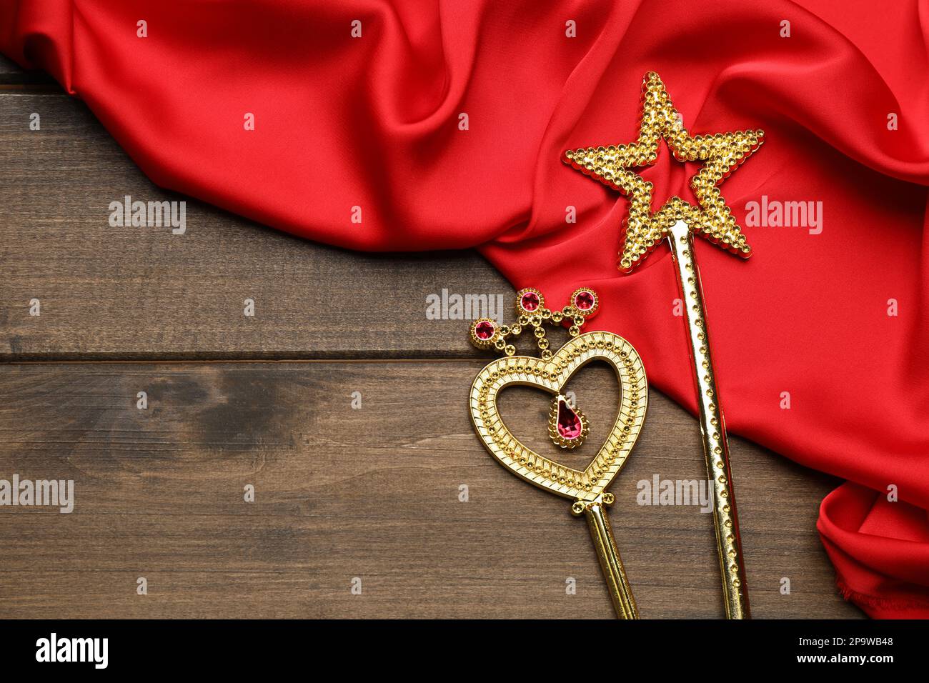 Different golden magic wands and red fabric on wooden table, flat lay ...