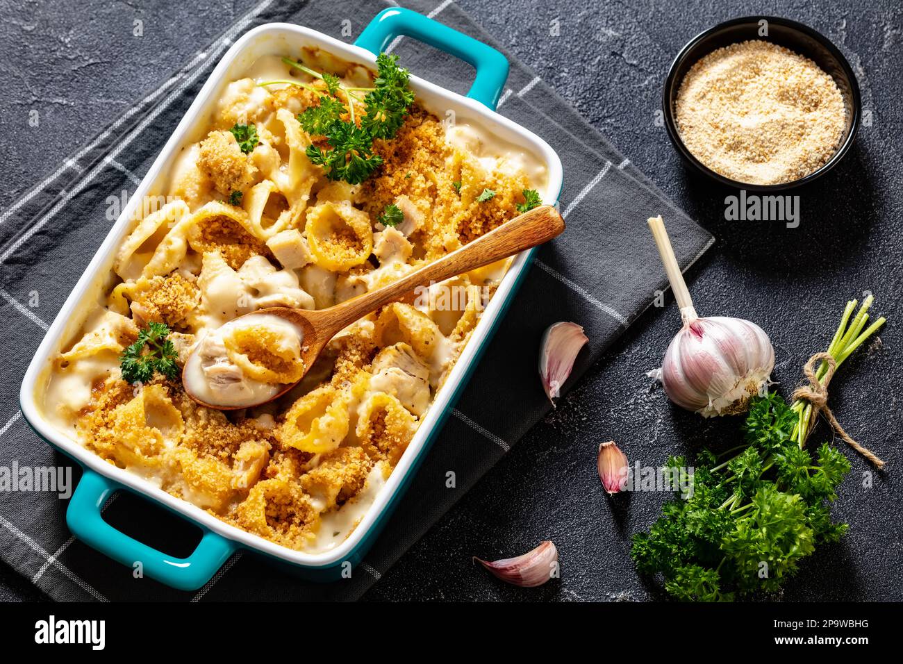 cheesy and creamy chicken and shells pasta bake in baking dish on dark ...