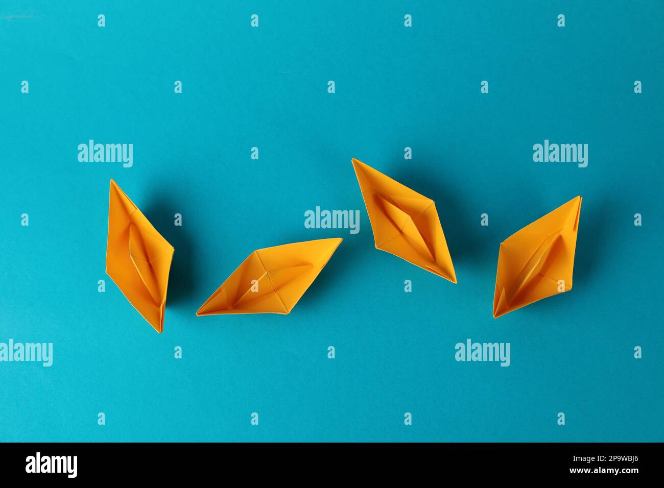 Handmade orange paper boats on light blue background, flat lay. Origami ...