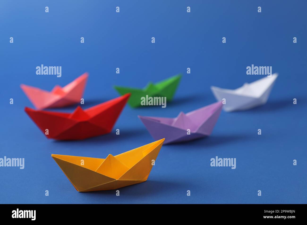 Many colorful handmade paper boats on blue background. Origami art ...