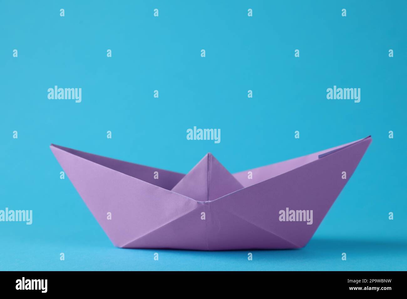 Handmade violet paper boat on light blue background. Origami art Stock ...