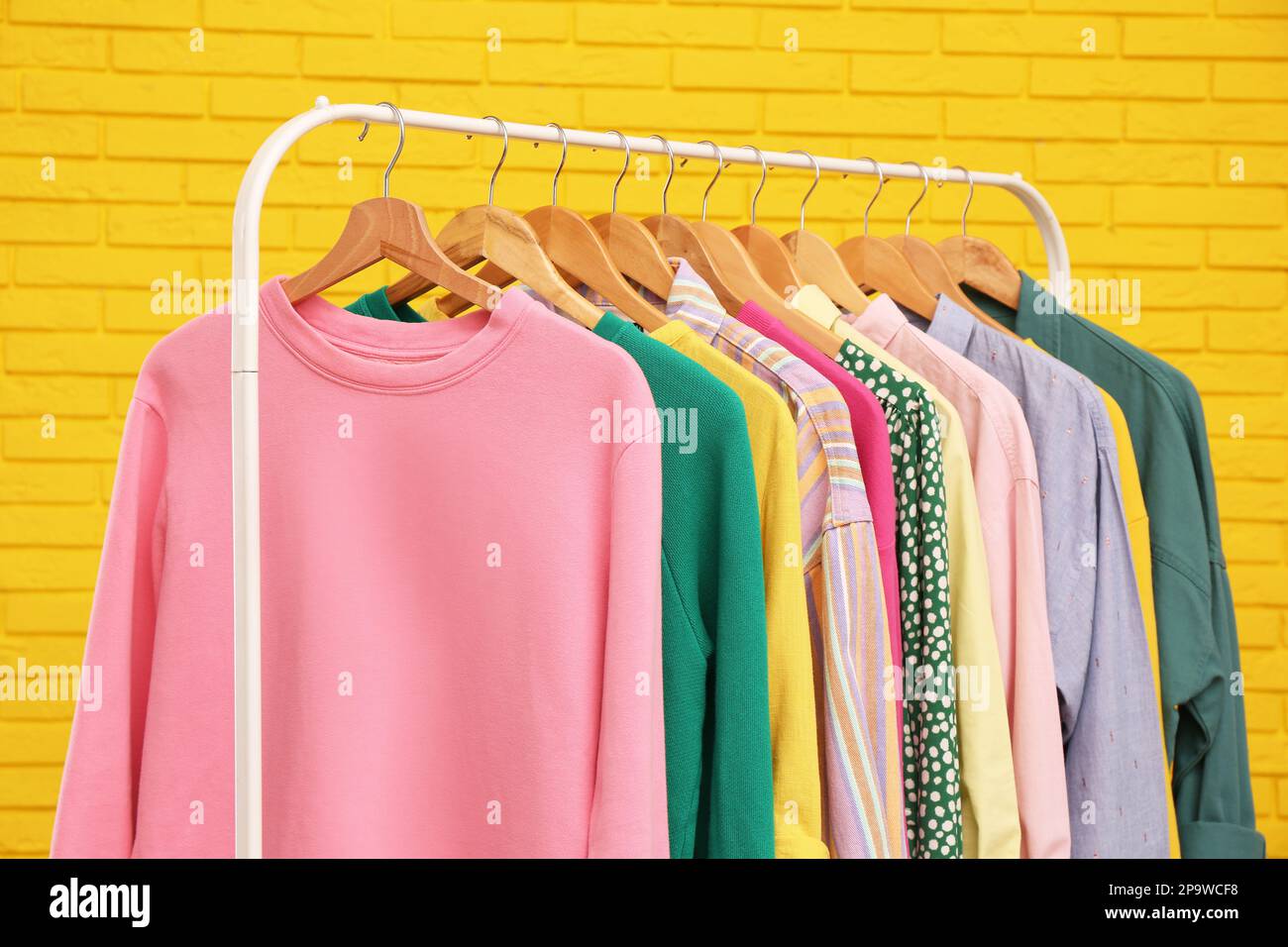 Rack with stylish clothes near yellow brick wall Stock Photo - Alamy