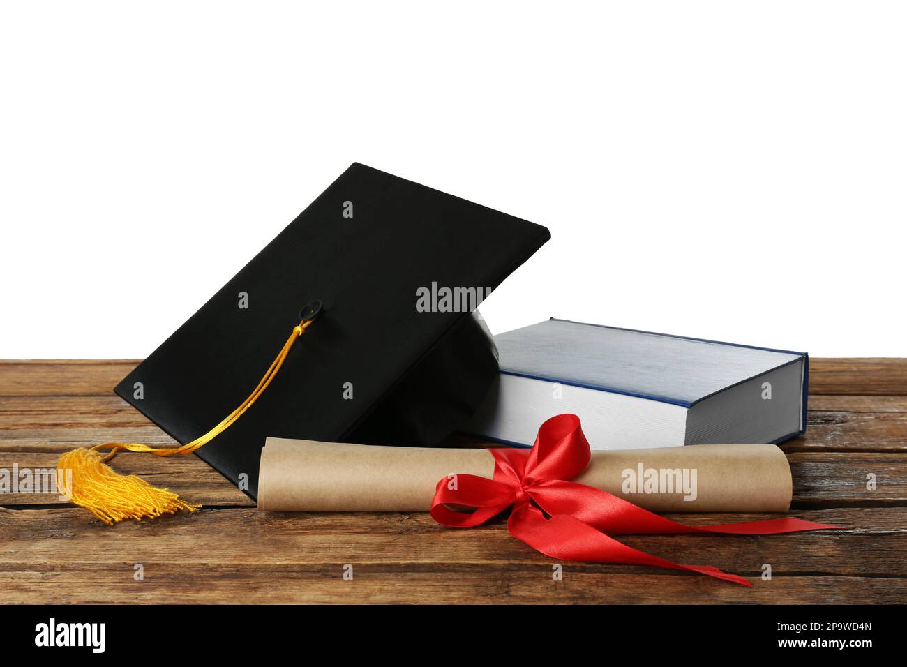 Graduation hat, book and diploma on wooden table against white ...