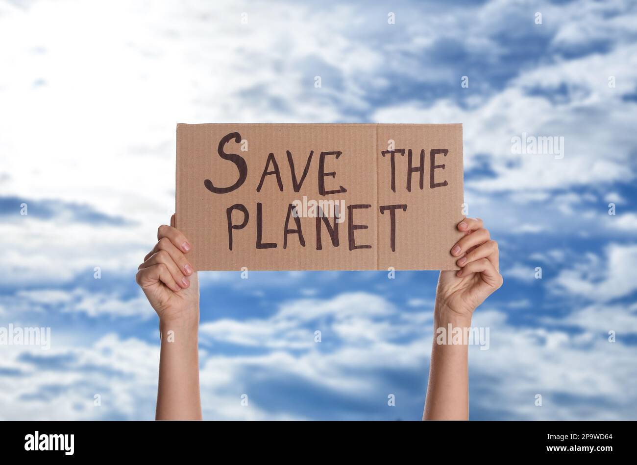 Protestor holding placard with text Save The Planet against blue sky ...