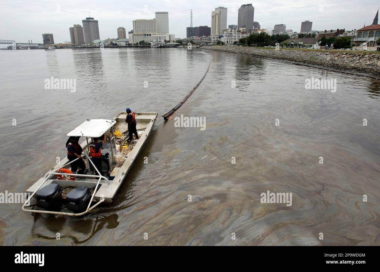 Workers place containment booms to contain fuel oil after a ship hit a ...