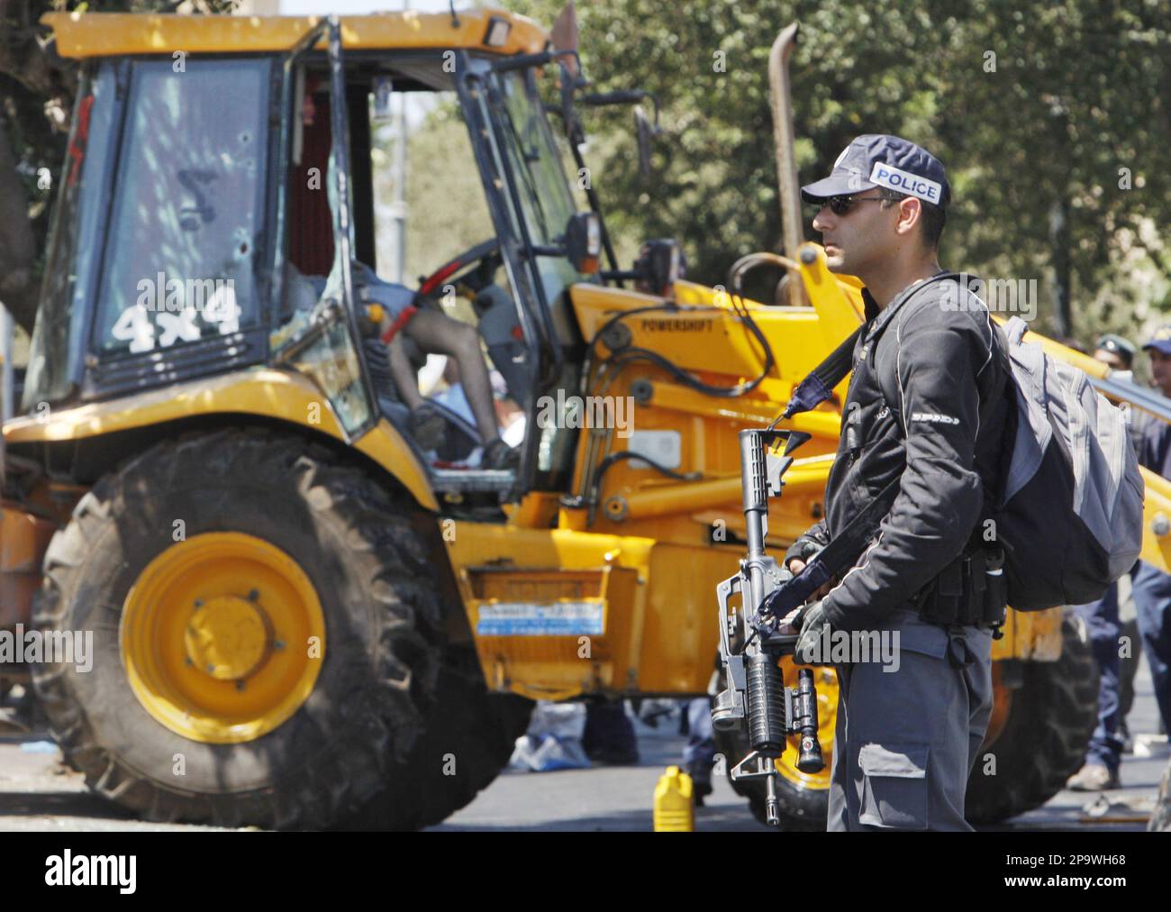 An Israeli security force officer stands guard next to a front-end ...