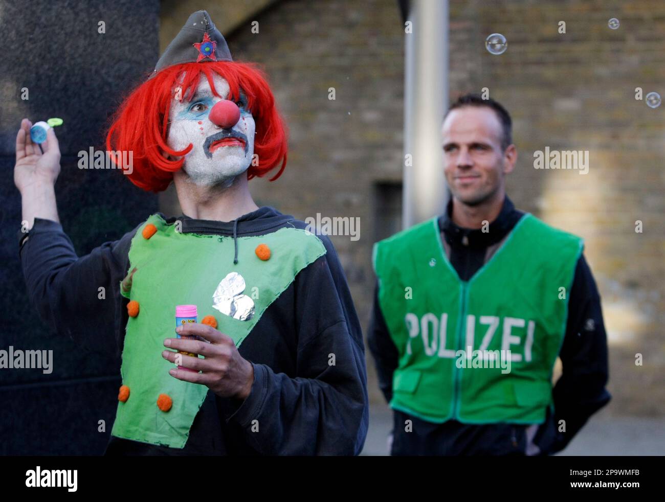 A man dressed like a clown blows soap bubbles during a protest against ...