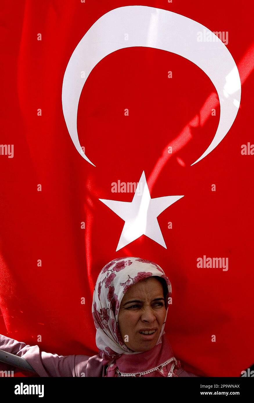 A Turkish woman satnds in front of a Turkish flag as she attends a ...
