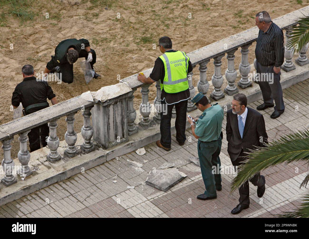 Police officers search the scene of a small bomb that exploded in the ...